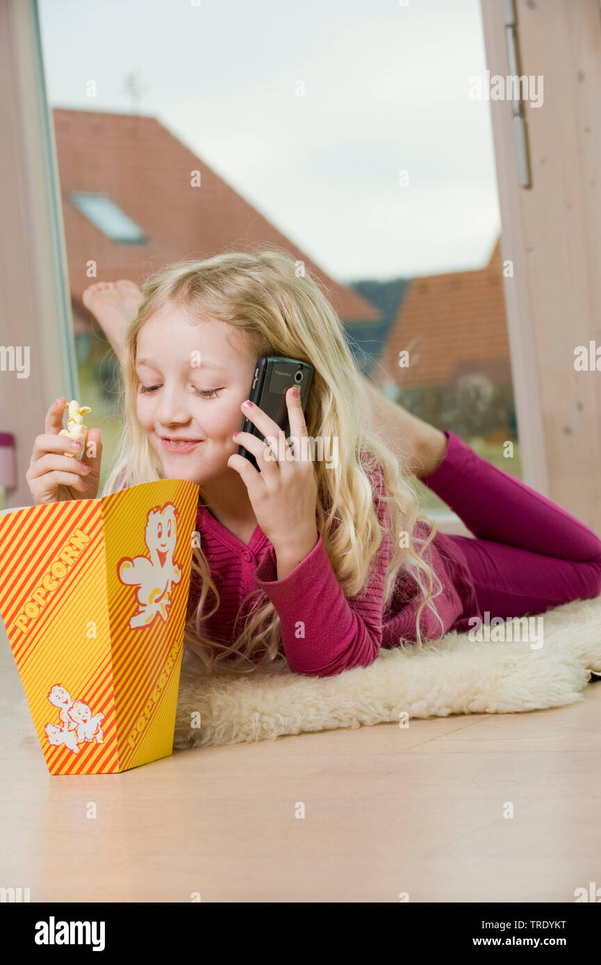 Portrait of a girl lying on the floor while making a phone call and ...