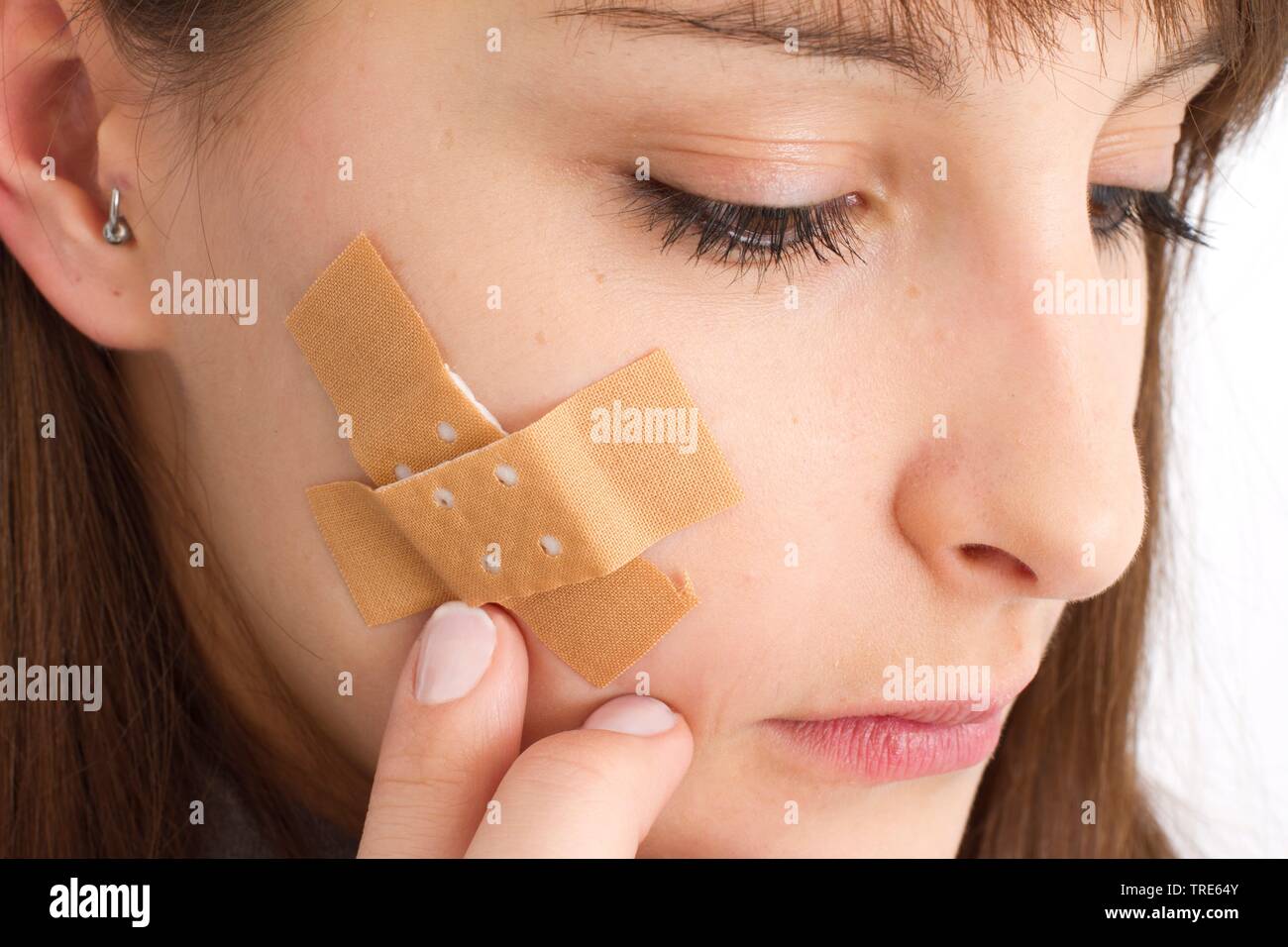 Young women with closed eyes, touching a plaster on her cheek Stock ...