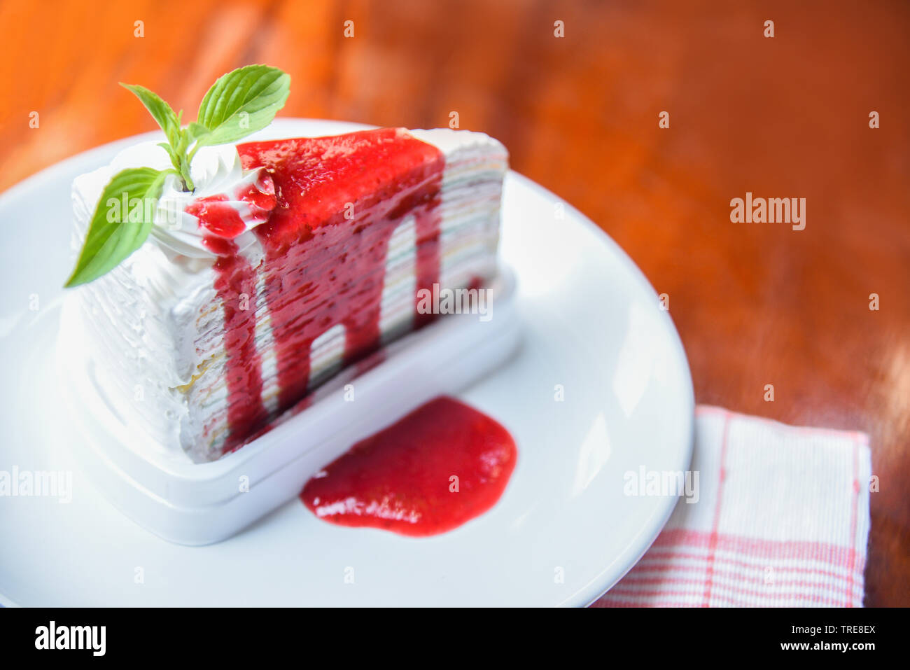 Crape cake slice with strawberry sauce on white plate on table wood ...