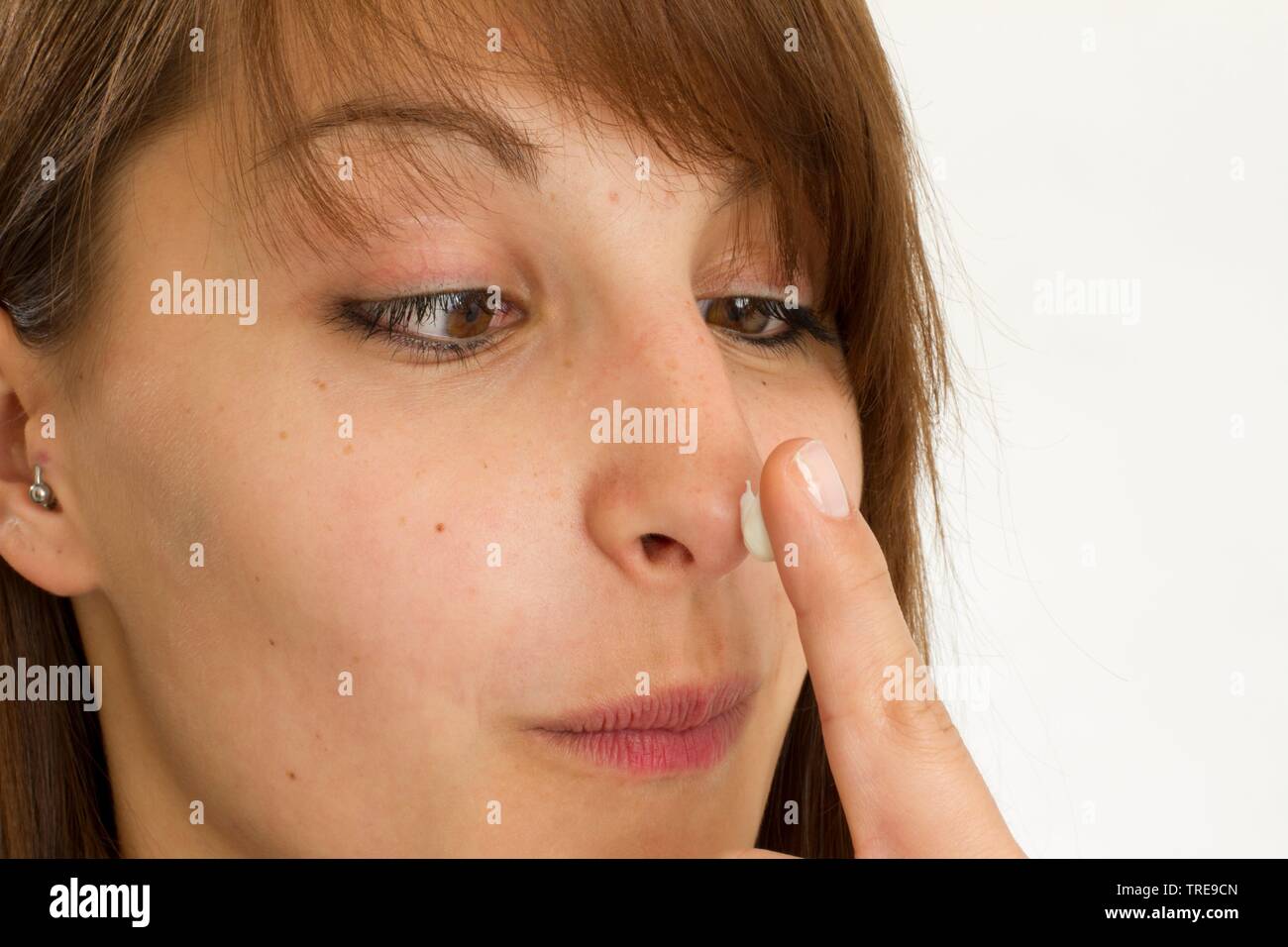 Young likeable women holding her finger with facial cream in front of ...