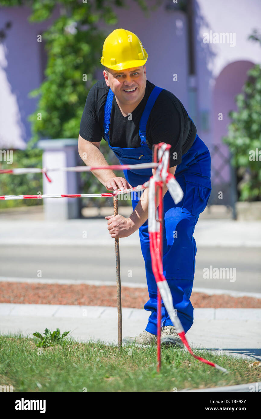 Construction worker, installing a barriers with warning tape Stock ...