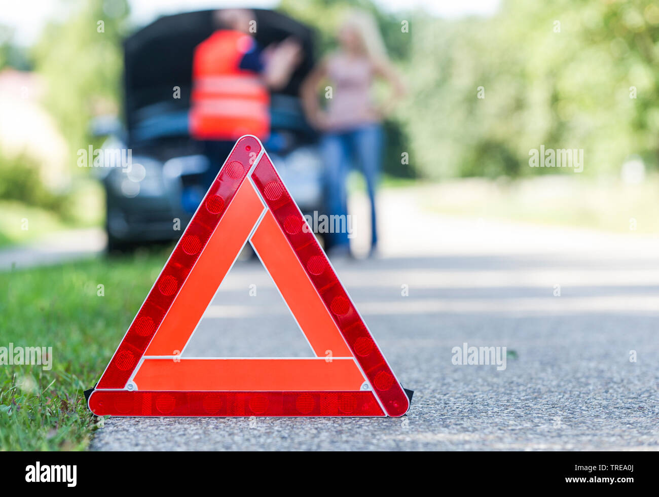 Triangular safety reflector at the side of the road with a broken down ...