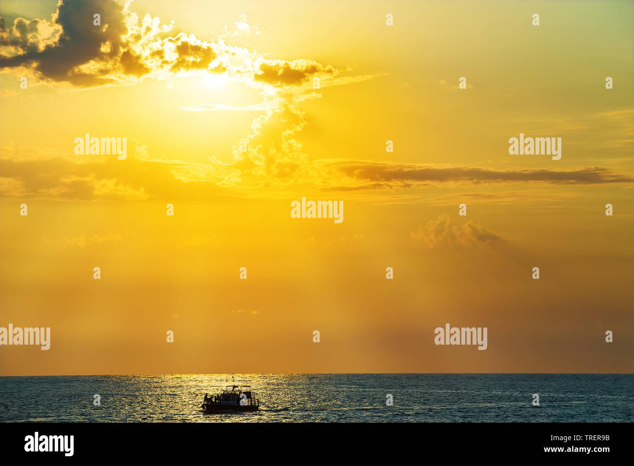 Boat with people in the sea at sunset Stock Photo - Alamy