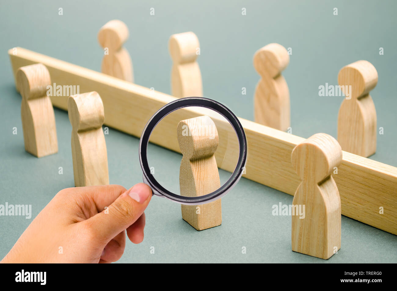 Wooden figures of people are separated by a barrier. Social classes ...