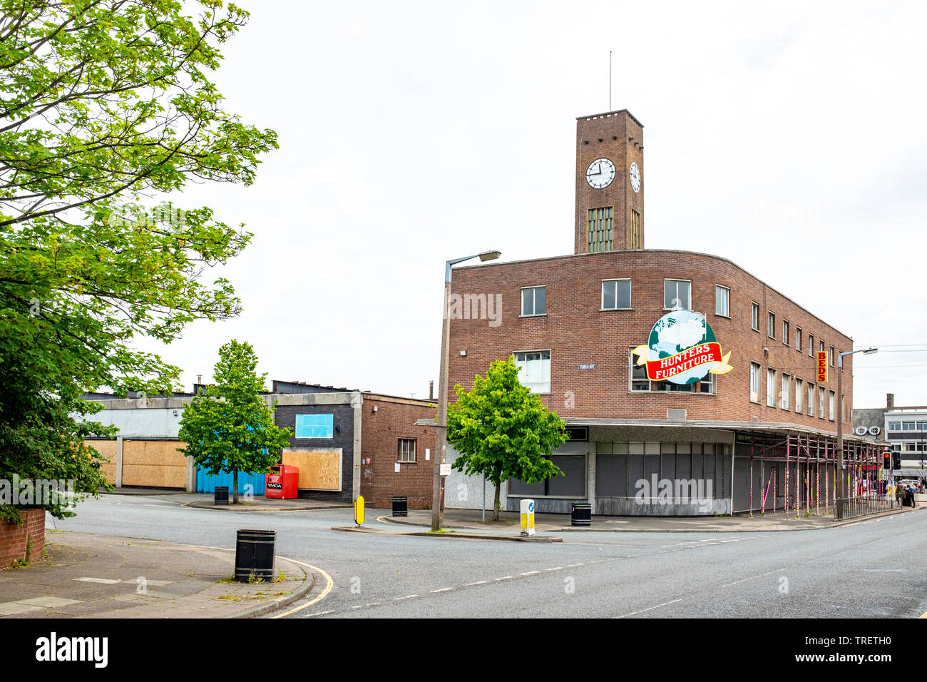 Clock tower with closed down and boarded up shops in the town centre of ...