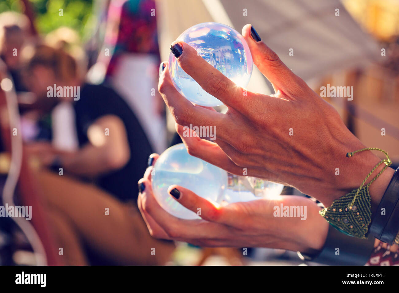 Sorcerer's hands holding juggling crystal balls at public summer ...