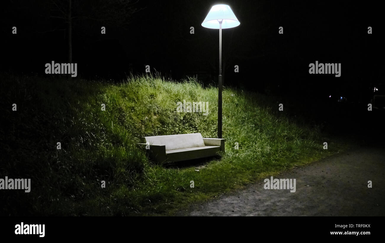 A bench that looks like a sofa under a street lamp that looks like a ...
