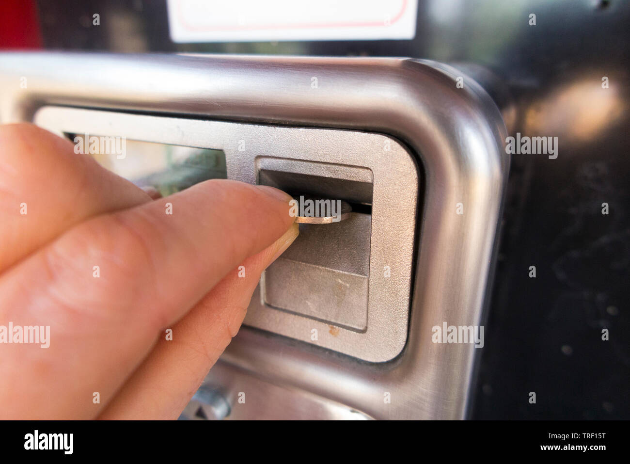 Person pushing a 20p coin into the slot of a late model coin operated ...