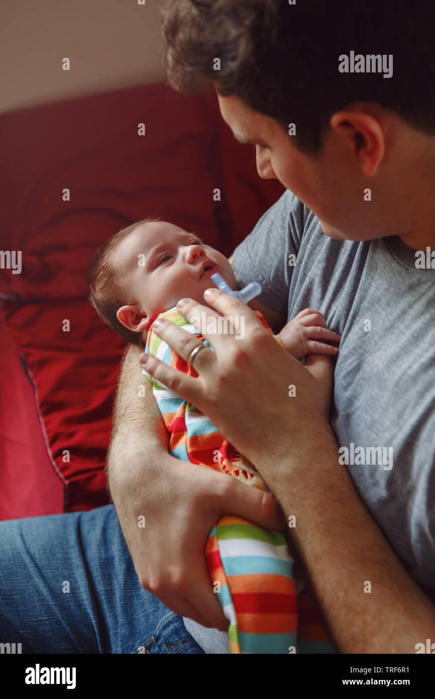 Young Caucasian father trying to calm down newborn baby. Male man ...