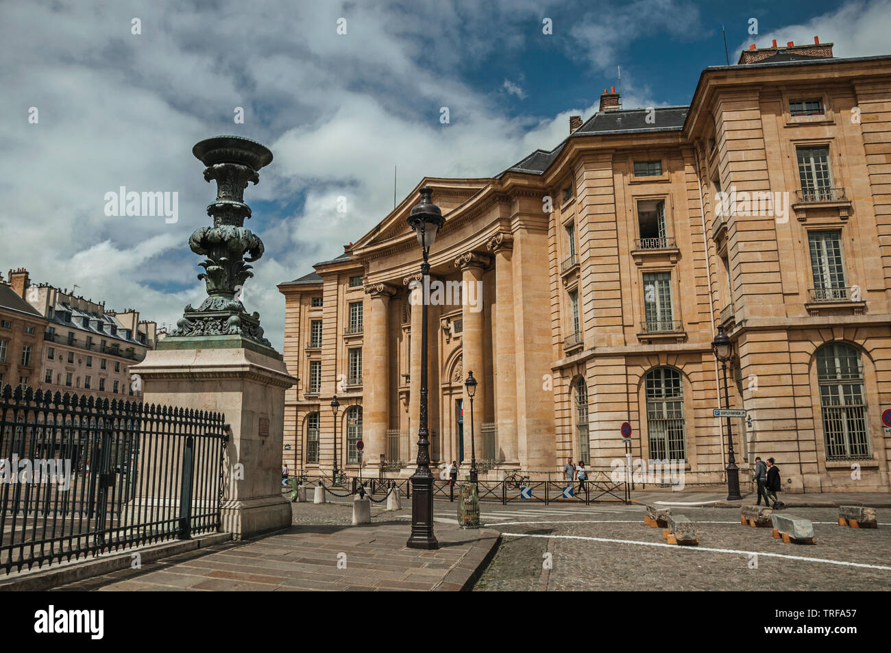 People in front of Neoclassical building, iron fence and blue sky in ...