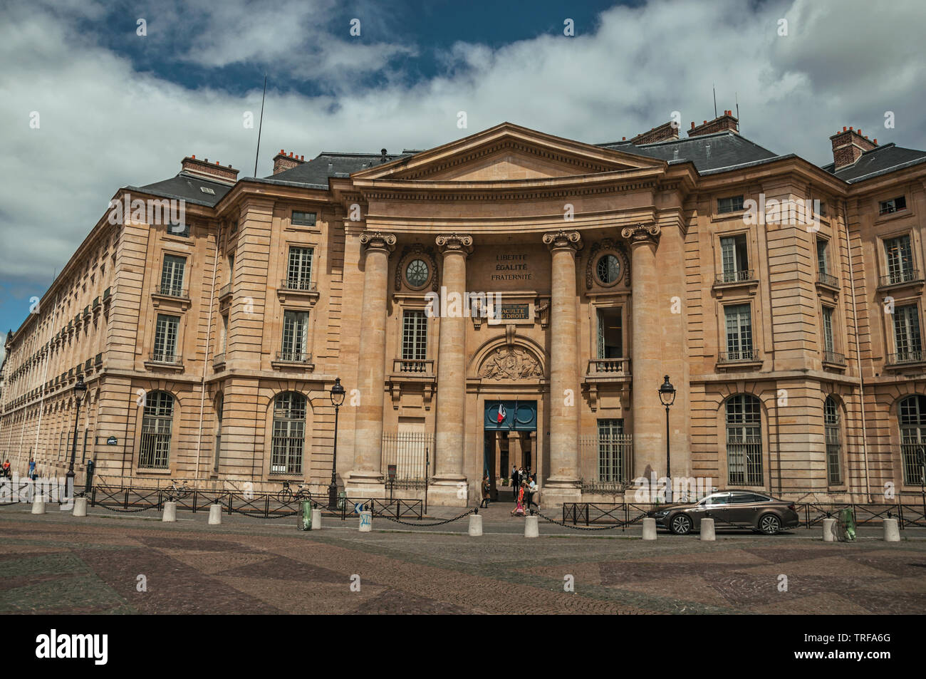 People in front Neoclassical building, cobblestone and cloudy sky in ...
