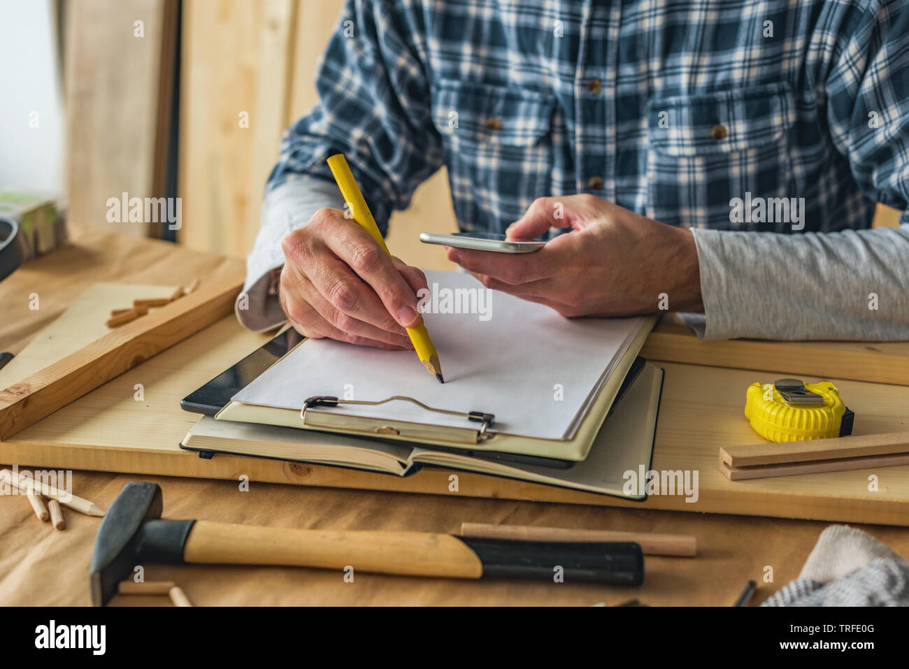 Carpenter using smart phone to complete project to do list in small ...
