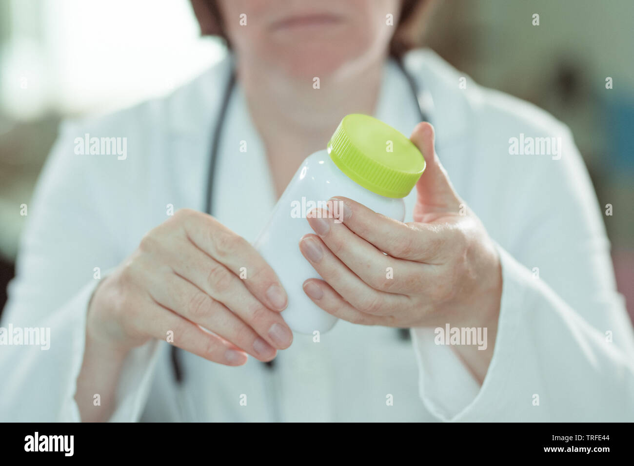 Female doctor holding bottle of dietary supplement in medical office ...