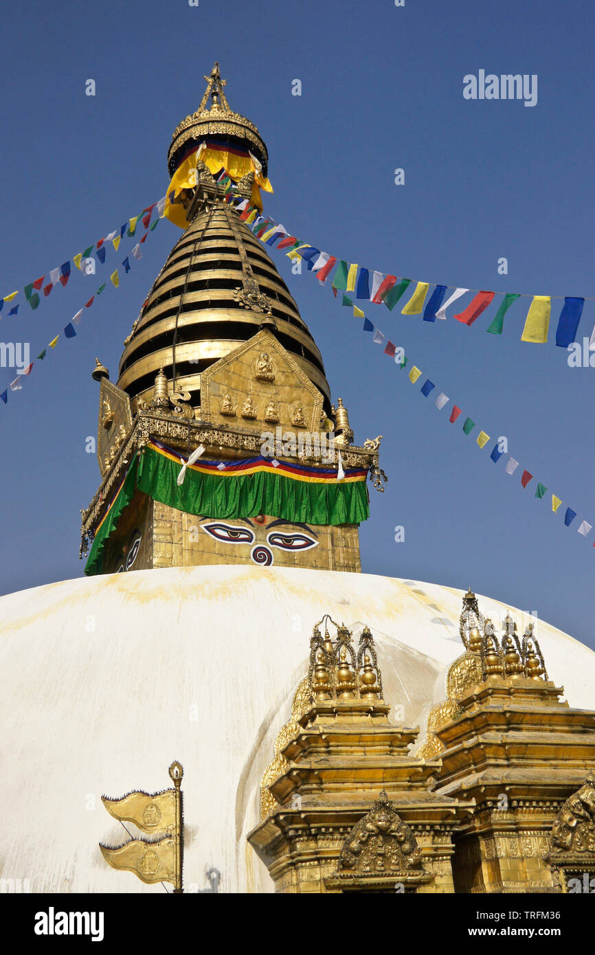 The gold spire and all-seeing eyes of Buddha atop a white-domed stupa ...