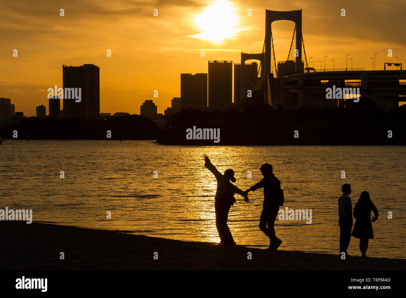 Two young couples enjoy the view of Rainbow Bridge from a beach in ...