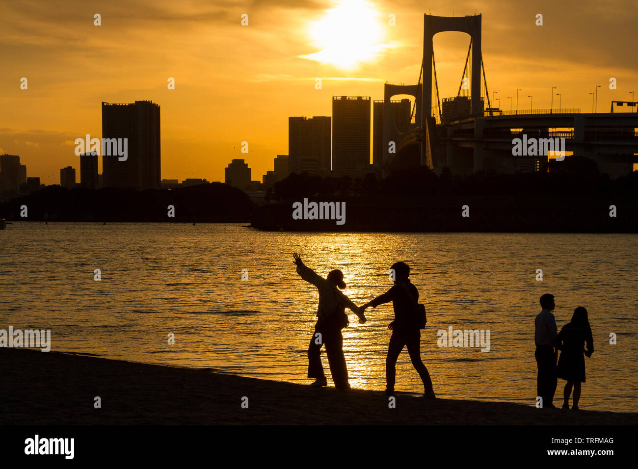 Two young couples enjoy the view of Rainbow Bridge from a beach in ...