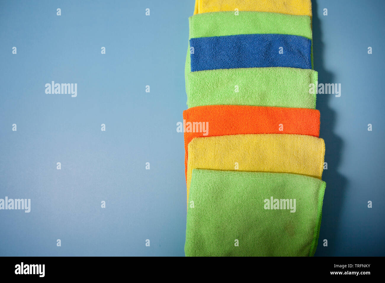 Yellow, green and orange cleaning rags folded into a pile beside a blue ...