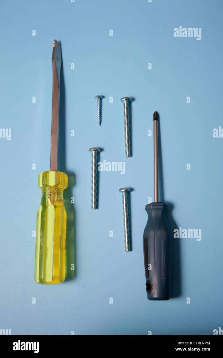 A few tools laying flat on a blue background including screwdriver and ...