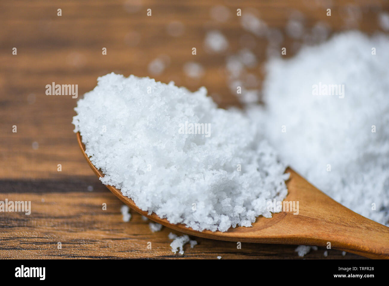 Salt in wooden spoon and heap of white salt on background Stock Photo ...