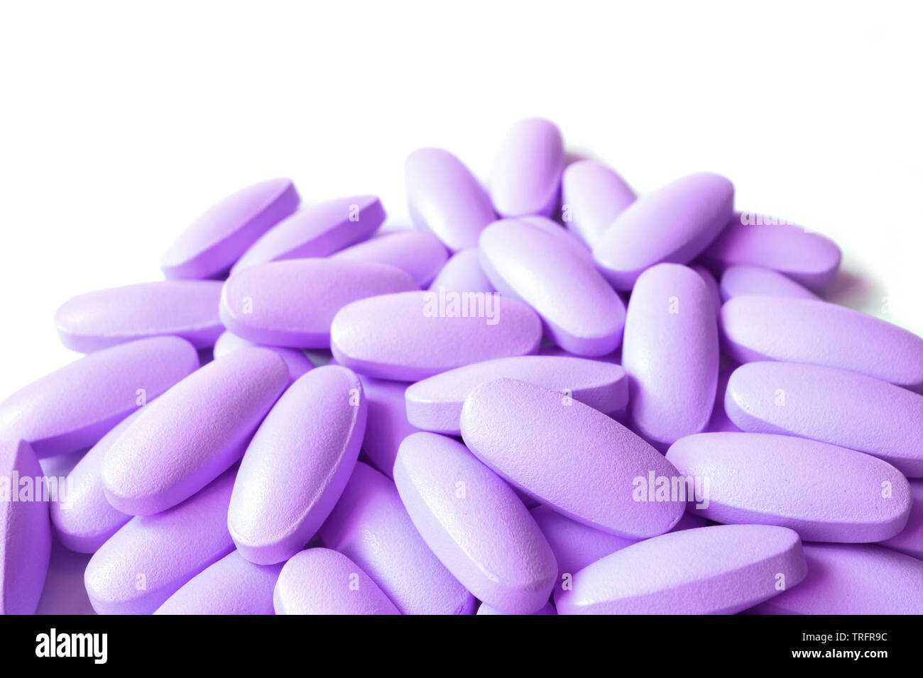 Pile of Lilac purple color oval shaped supplement pills on white ...