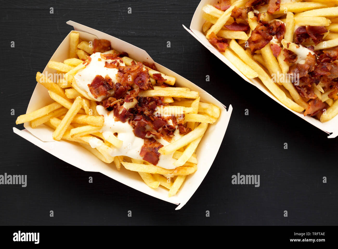 Top view, french fries with cheese sauce and bacon in paper boxes over ...