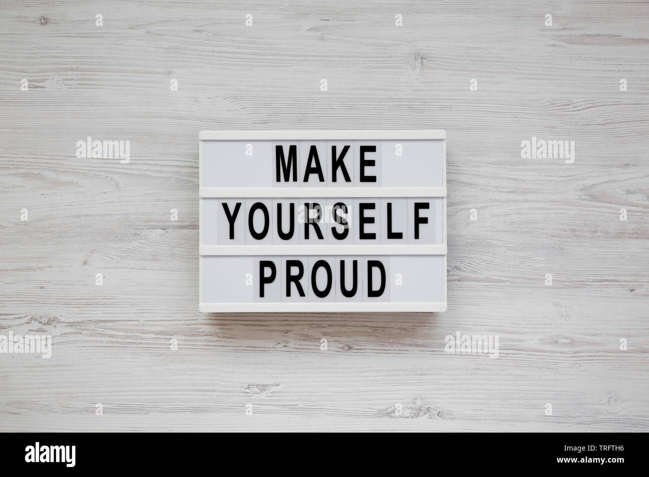 'Make yourself proud' words on a light box over white wooden background ...