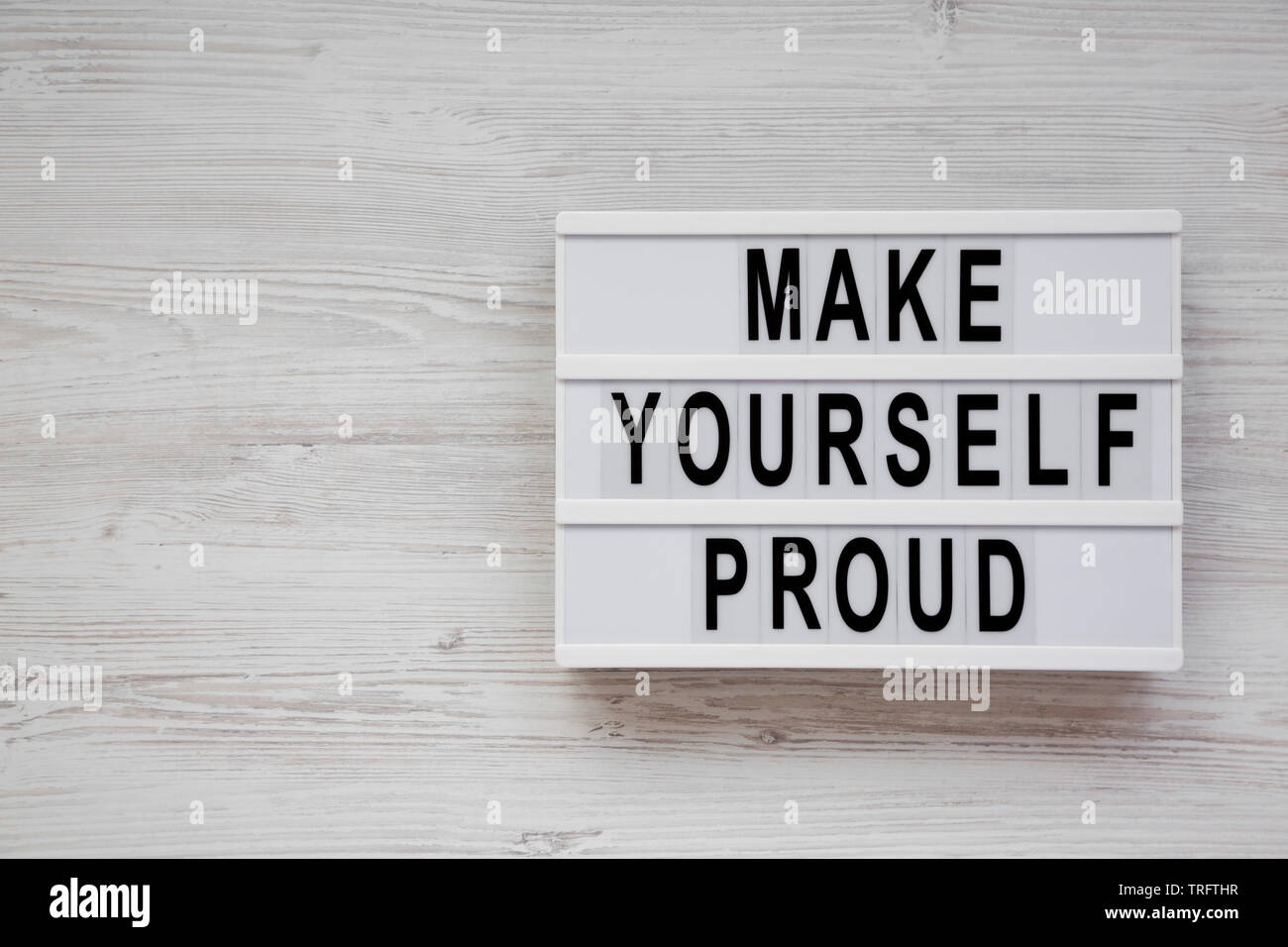 'Make yourself proud' words on a lightbox over white wooden surface ...