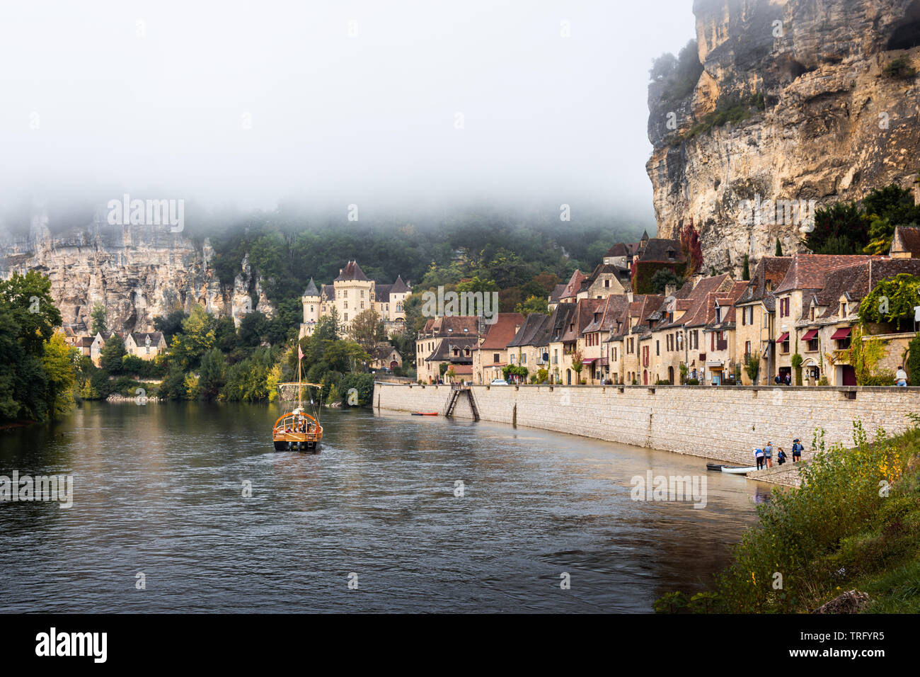 A traditional boat sails along the Dordogne River in front of the ...