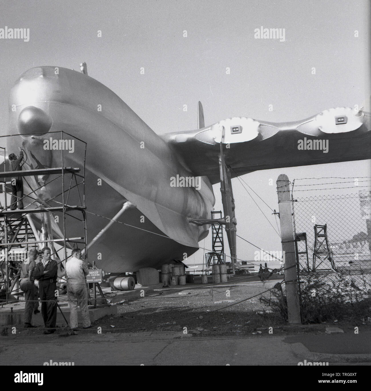 1950s, historical, workers in overalls outside at an industrial boat ...