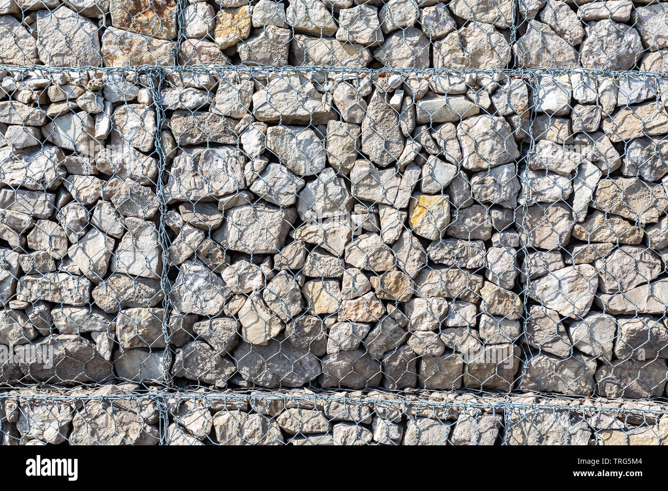 Stone wall with metal grid as background. Rock texture Stock Photo - Alamy