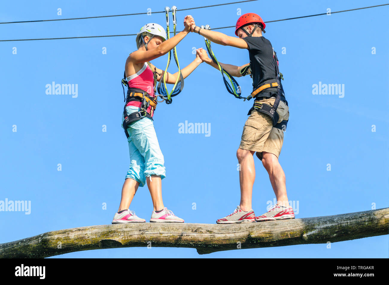 Partner exercise for teamwork in a high ropes course Stock Photo - Alamy