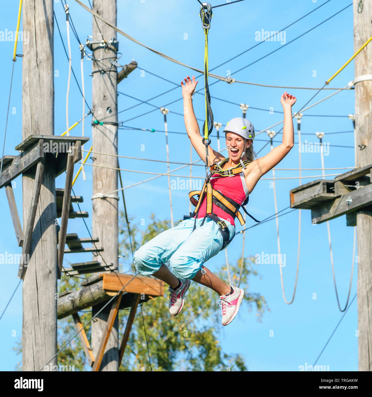 Young woman has a lot of fun while sliding downward in a flying fox ...