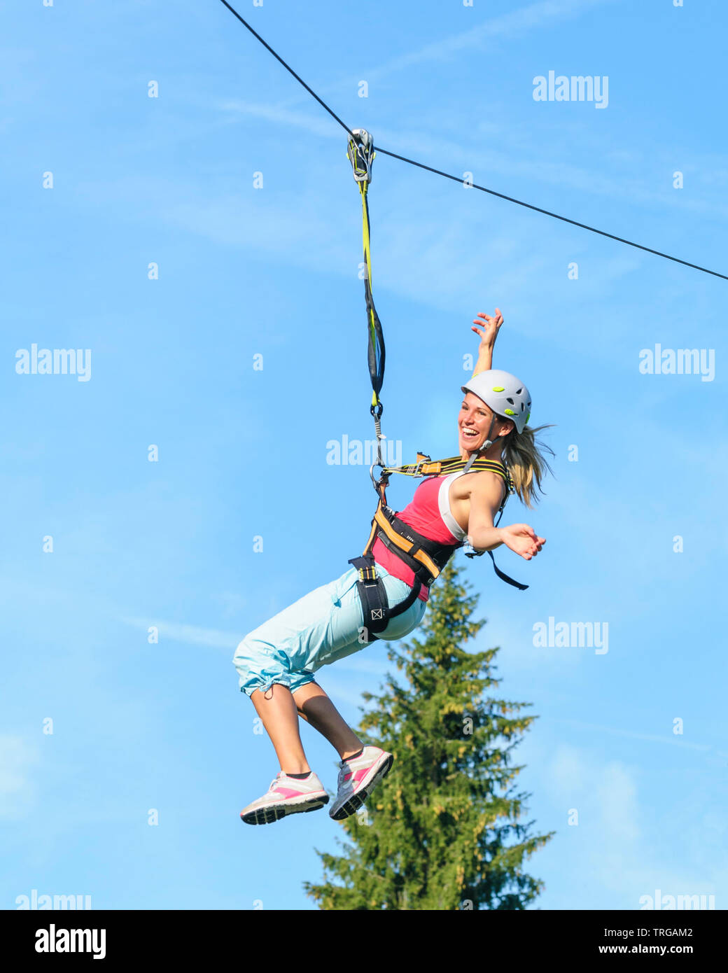 Young woman has a lot of fun while sliding downward in a flying fox ...