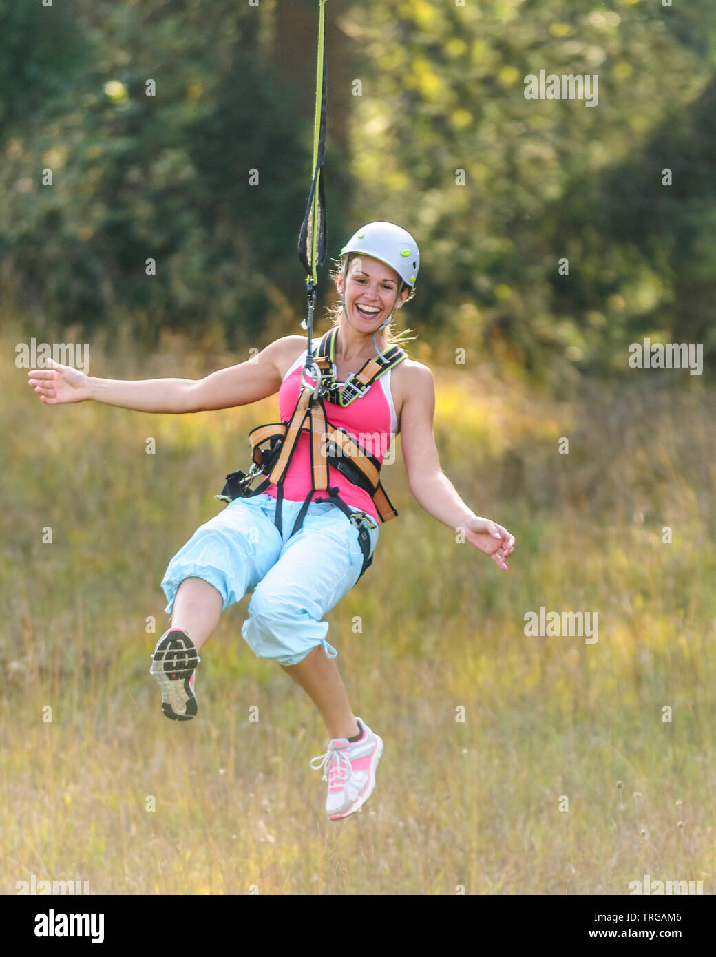 Young woman has a lot of fun while sliding downward in a flying fox ...