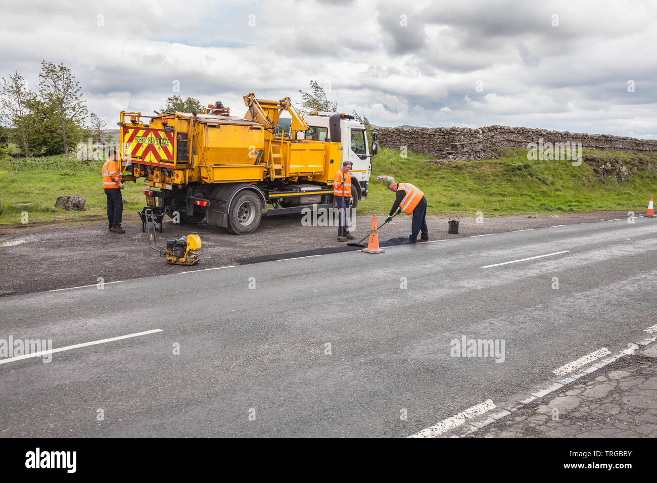 Three workmen repairing potholes on the road surfaces in Teesdale ...