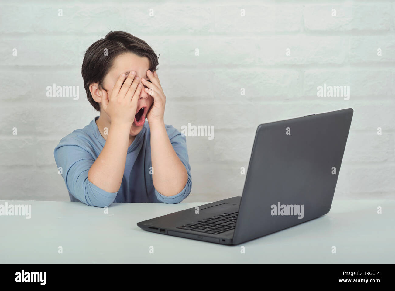 Little boy watching inappropriate content on laptop computer on brick ...