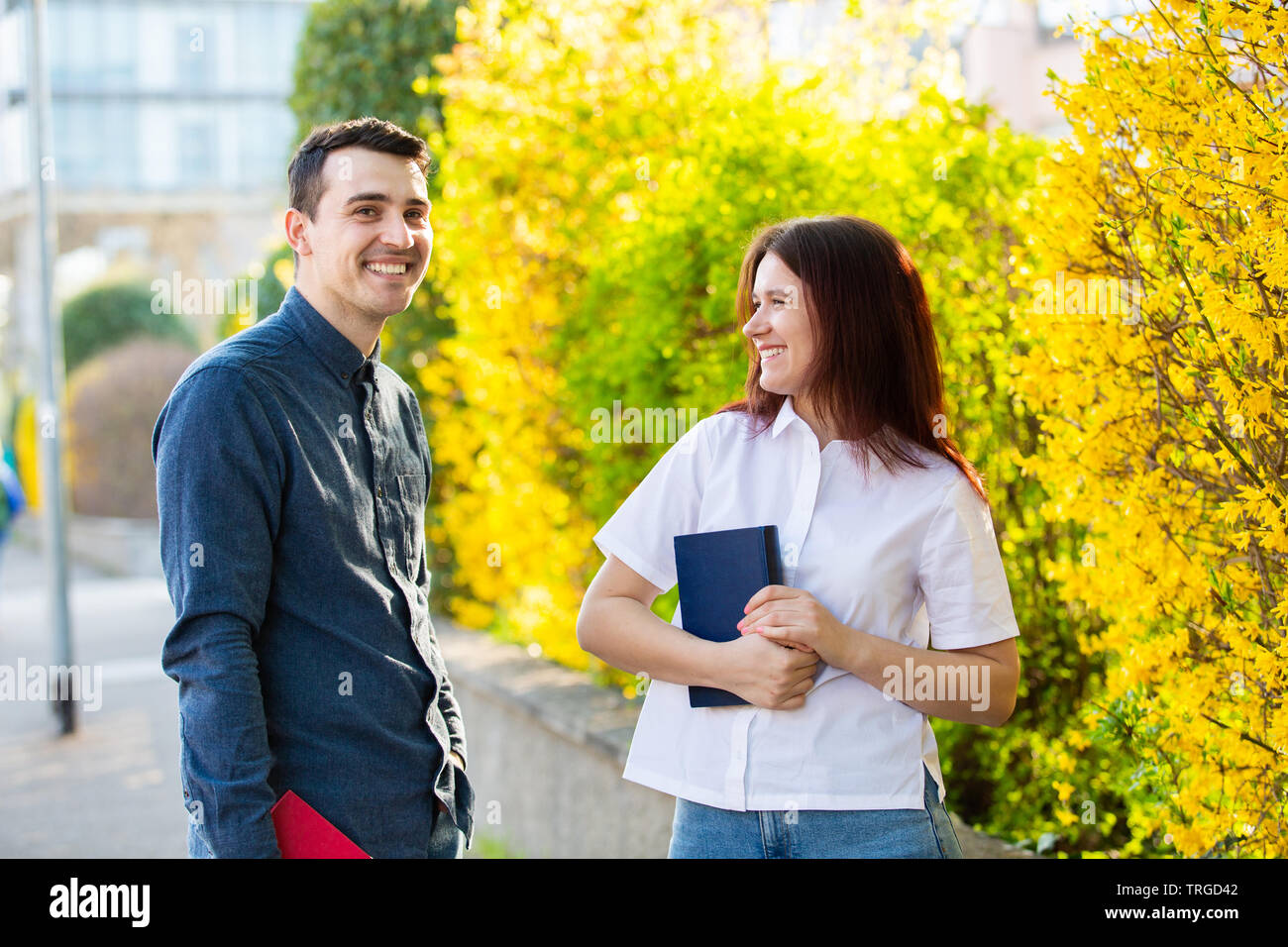 Smiling students taking a break from exam task together in a city park ...