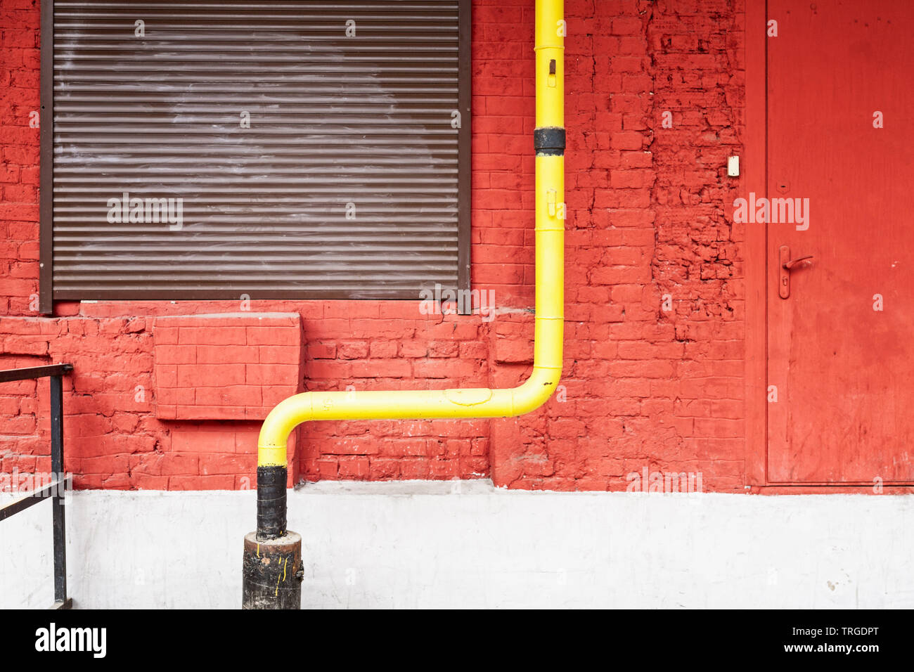 Old brick wall building exterior in coral color with yellow pipe ...