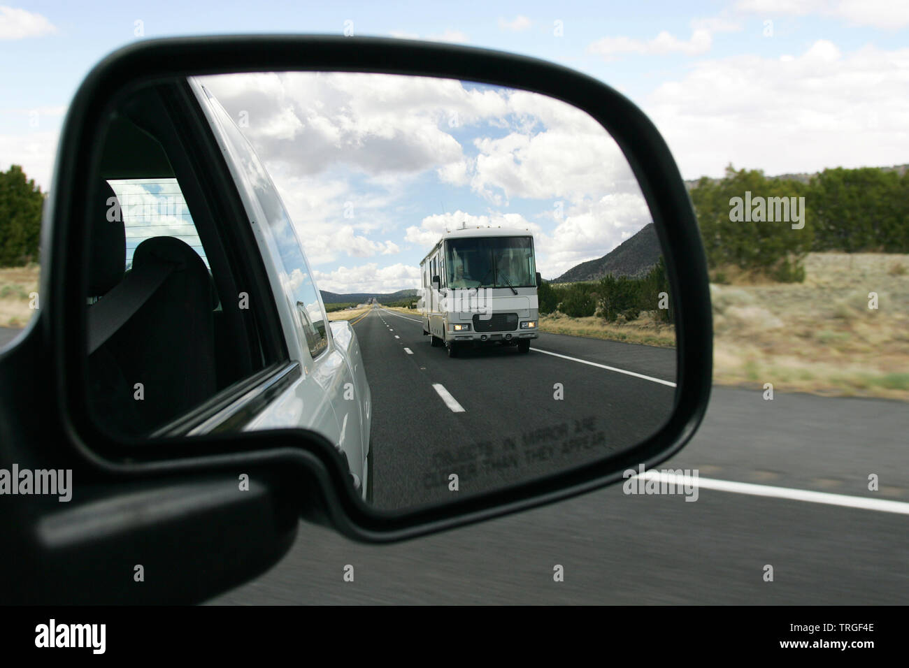 A view of an RV driving down the highway reflecting in a rear view ...