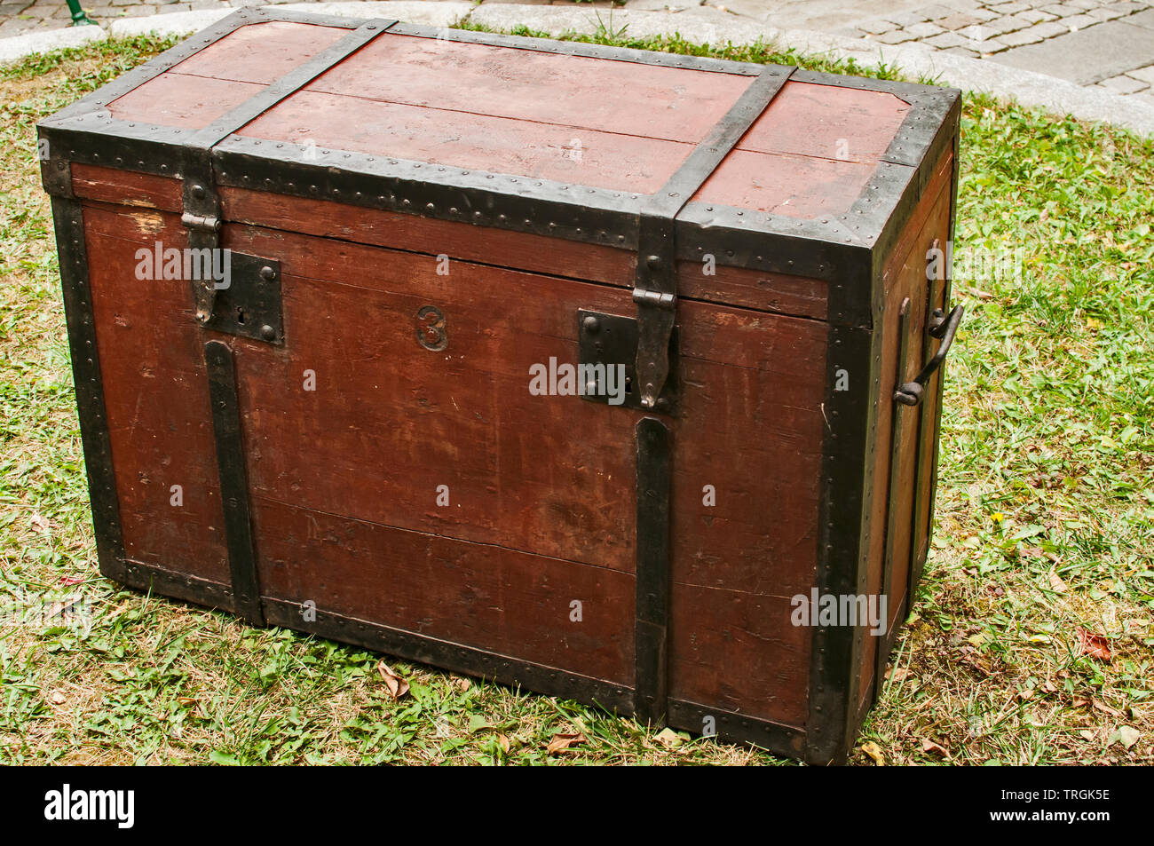 Old vintage retro wooden chest with iron strapping on green grass house ...