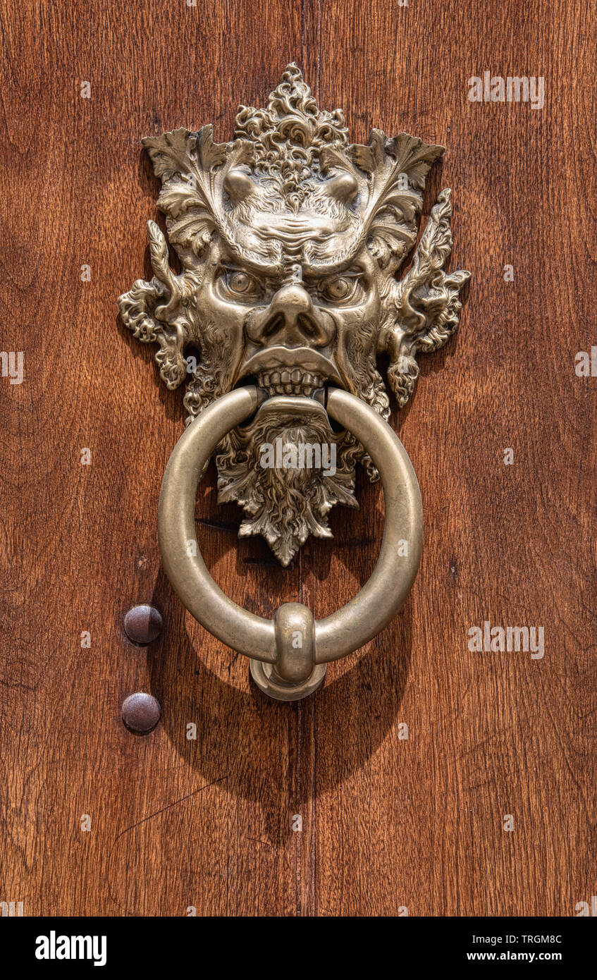 Photograph taken of a carved metea devil door knocker on a brown ...