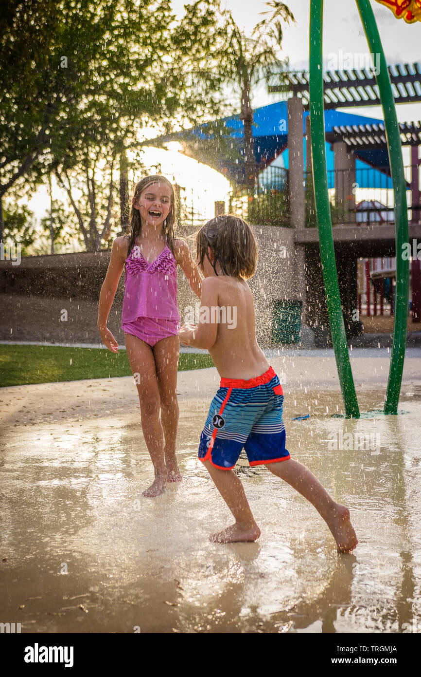 Boy and Girl playing at a Splash Pad in the summer Stock Photo - Alamy