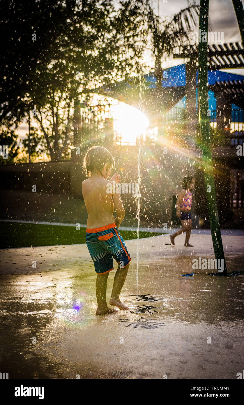 Boy and Girl playing at a Splash Pad in the summer Stock Photo - Alamy