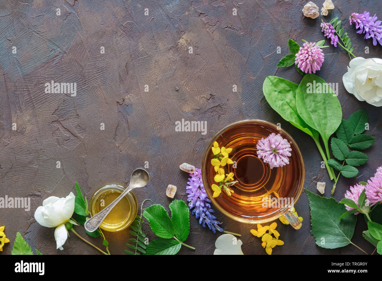 Glass mug of healthy herbal tea, medicinal herbs and small honey jar ...