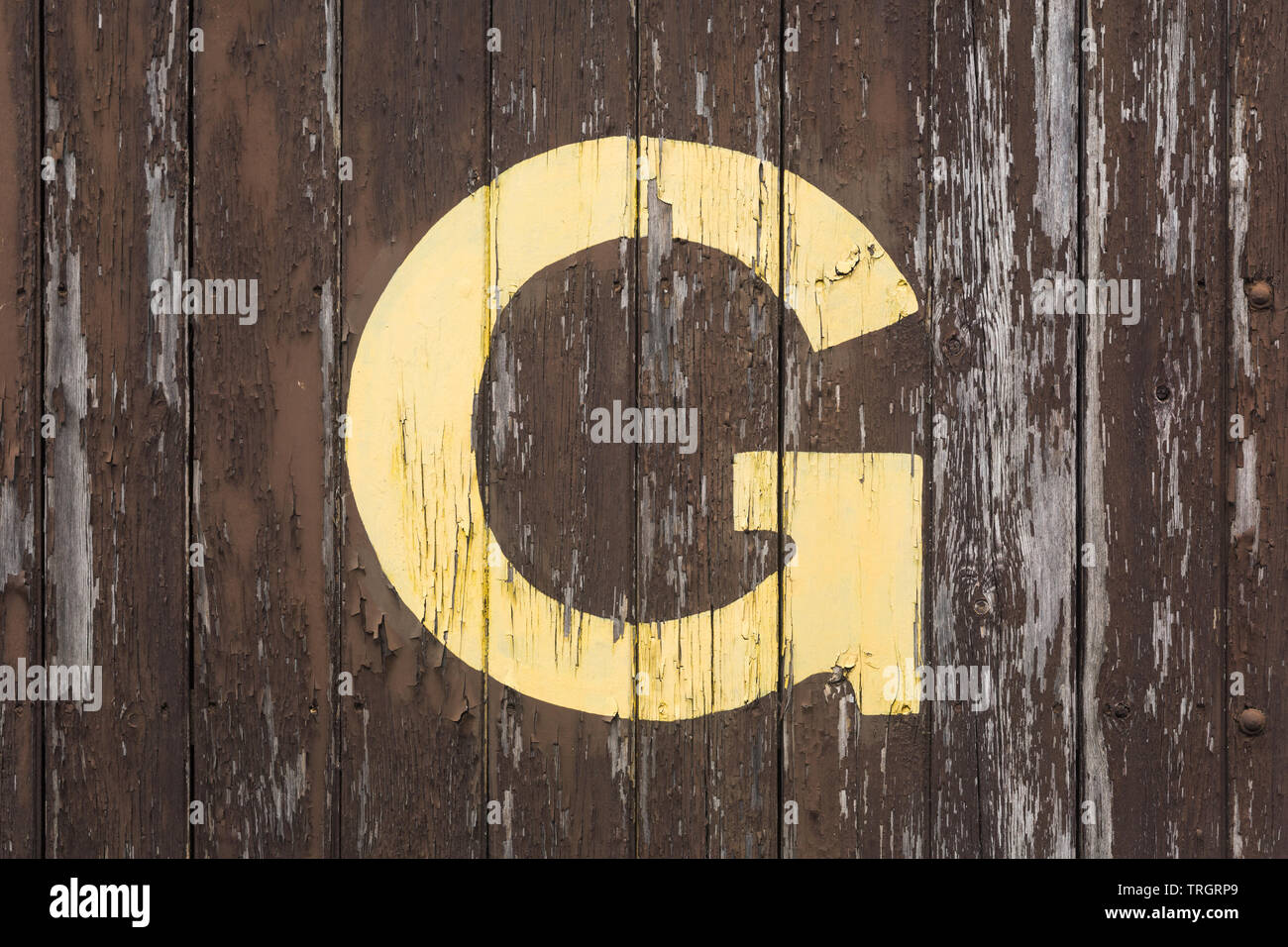 Large painted yellow letter "G" from GWR surrounded by peeling brown ...