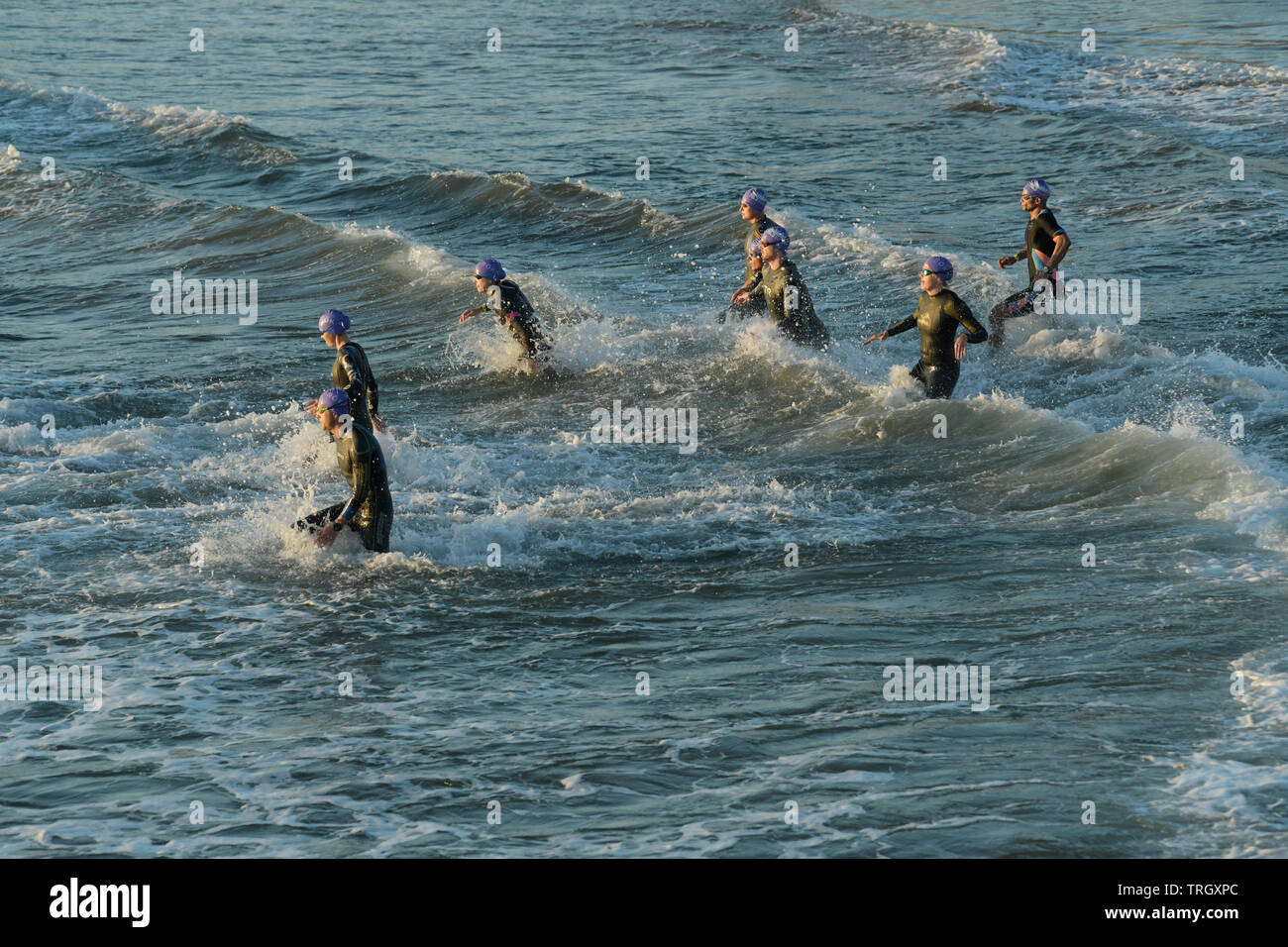 Group of elite triathletes wading through surf, swimming leg, triathlon ...