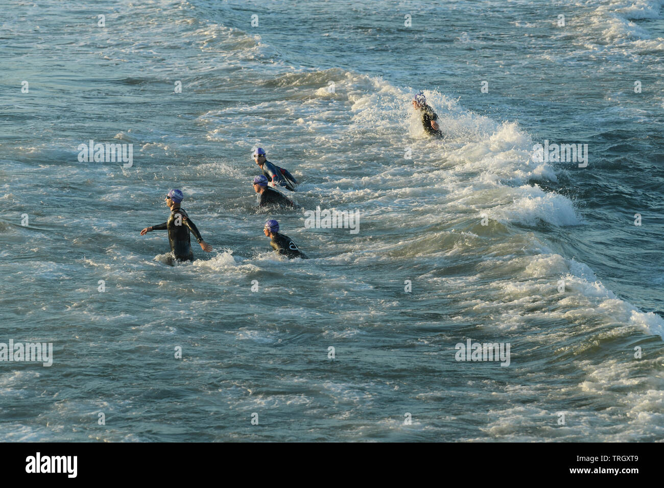 Group of triathletes wading through surf, start swimming race, 2019 ...