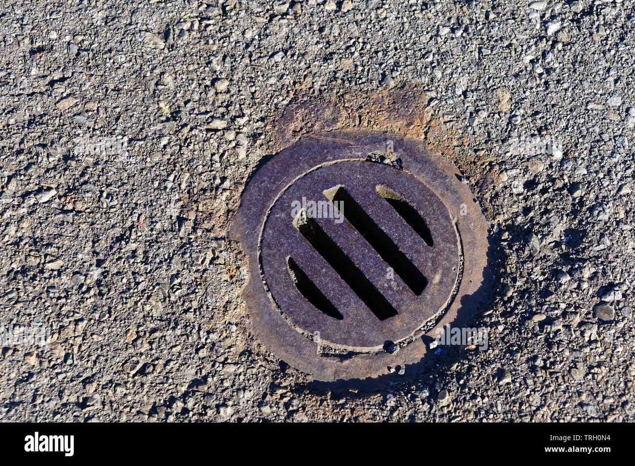 A drain is covered by a round, rusty grate Stock Photo - Alamy