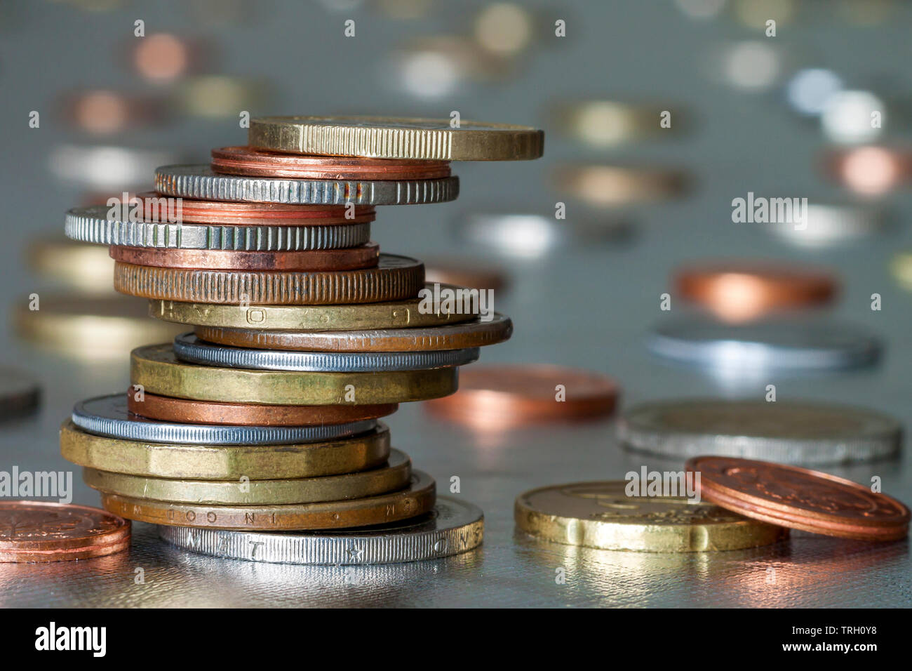 Pile of shiny coins different sizes and colors stacked unevenly on each ...
