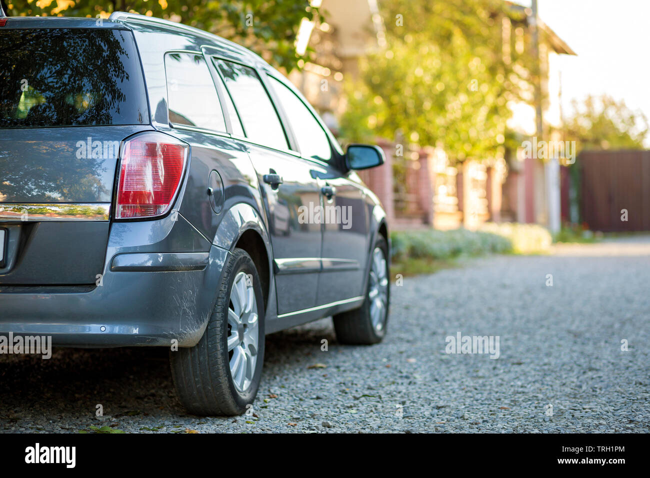 New shiny gray car parked on gravel suburbs road on blurred sunny ...